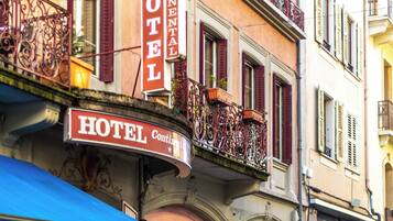 Um hotel com uma placa que diz 'HOTEL Continental', área de estar externa e um homem parado perto da entrada.