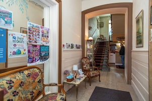 Uma área de recepção com escada, balcão e sala de espera com mobiliário estampado com motivos florais.
