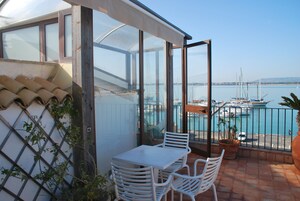 Uma varanda com mesa e cadeiras, com vista para uma marina cheia de barcos.