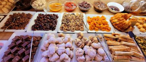 Diversos pastéis e acompanhamentos expostos numa pastelaria ou café.
