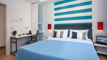 Quarto de hotel moderno com uma cama grande, uma escrivaninha e um computador.