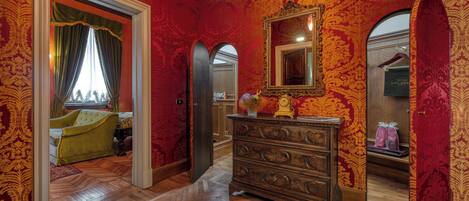 Quarto com papel de parede decorativo, penteadeira de madeira e espelho.