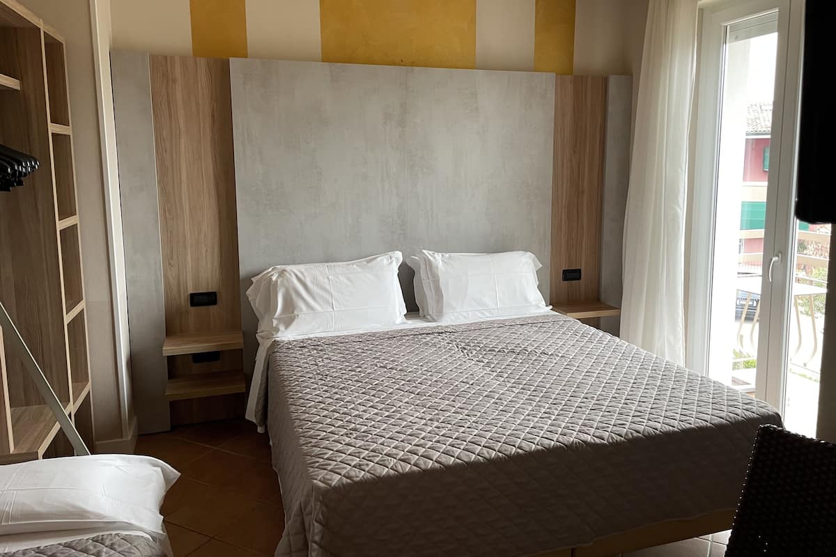 Quarto de hotel com cama, guarda-roupa e janela com cortinas.