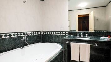 Casa de banho com banheira, pia e espelho.
