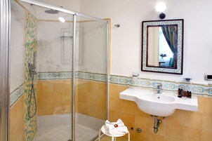 Um banheiro com box de vidro, pia com espelho e azulejos decorativos.