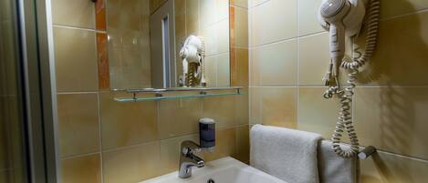 Casa de banho com lavatório, espelho, porta-toalhas e secador de cabelo fixado na parede.