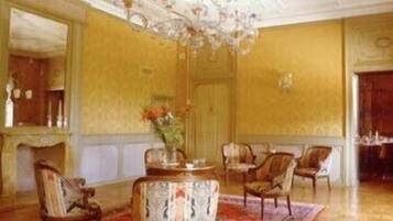 Um quarto com um candelabro, uma mesa redonda com cadeiras e um espelho grande.