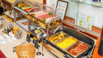 Buffet com diversas opções de comida, incluindo carnes, legumes e frutas.
