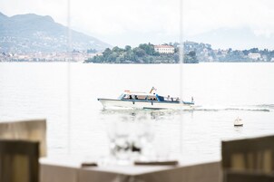 Um barco em um lago calmo, com vista distante de uma cidade e montanhas.