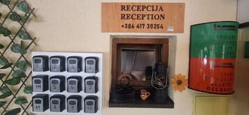 Uma área de recepção com placa de madeira, teclado telefônico, janela com vista e placa verde e vermelha.
