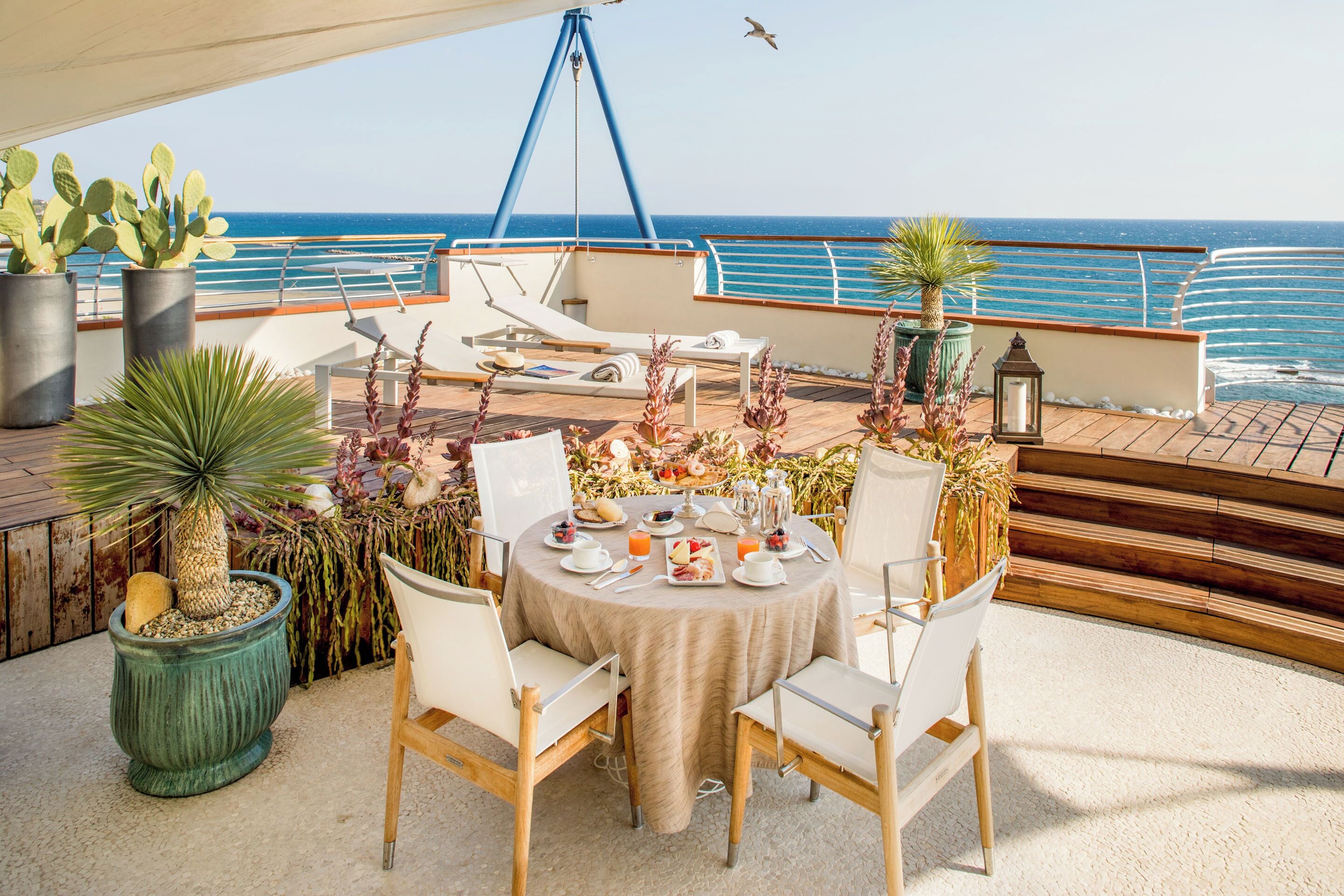 Mesa redonda com cadeiras em um deck, com vista para o mar.