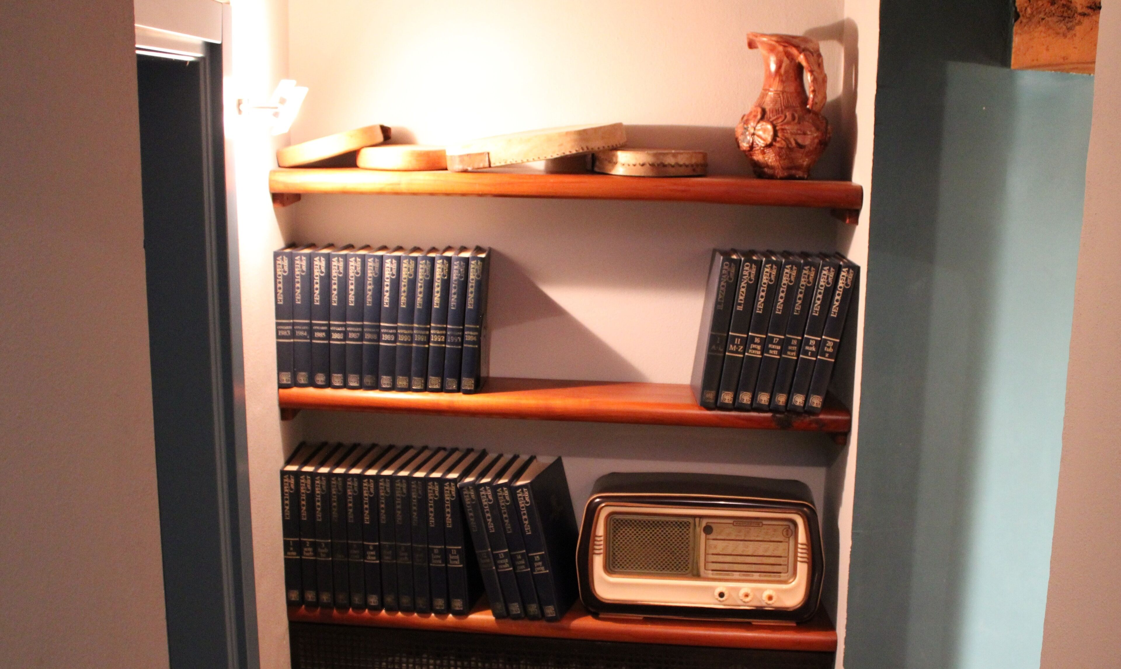 Uma estante com várias fileiras de livros e um rádio antigo.