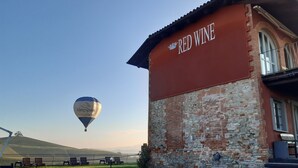 Um edifício com um letreiro de vinho tinto, piscina e um balão de ar quente ao fundo.