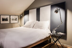 Quarto moderno com uma cama grande, duas luminárias laterais e uma mesinha de cabeceira com abajur.