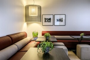 Uma área de estar moderna com sofá, mesas e plantas em vasos.