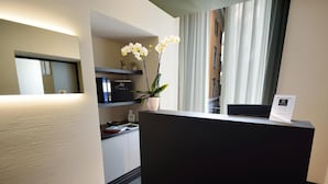 Um balcão de atendimento moderno com uma orquídea em vaso, uma tela digital e uma placa indicando uma sala privativa.