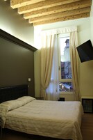Quarto com cama, janela com cortinas, TV de tela plana na parede e teto de madeira.