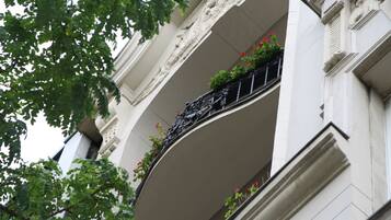 Fachada de edifício com varandas decoradas com flores vermelhas e grades pretas.