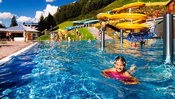 Piscina com toboáguas e uma pessoa nadando.