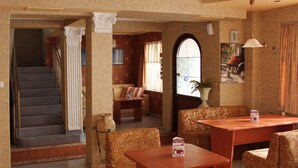 Um saguão de hotel com escadas, área de estar e uma mesa de jantar.