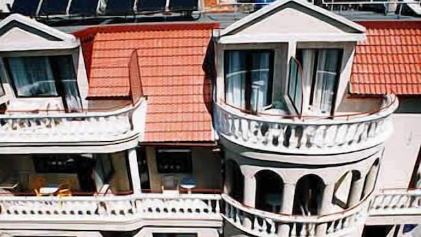 Um edifício com várias andares, varandas e uma estrutura que lembra uma torre.