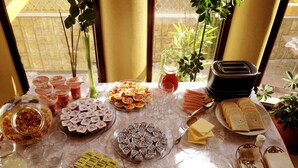 Uma mesa com diversos alimentos e acompanhamentos, incluindo potes de geleia, um prato de pão e um jarro de suco.