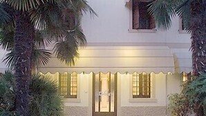 Um edifício com fachada branca, portão e três janelas com persianas.