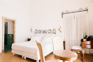 Quarto com uma cama, duas cadeiras, uma mesinha e cortina.