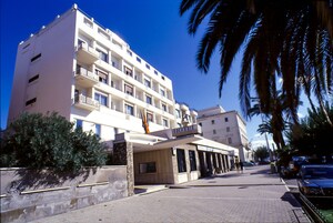 Um hotel com vários andares, varandas, entrada no nível da rua e calçada pavimentada.