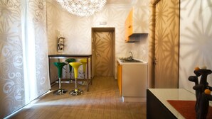 Uma cozinha compacta com uma ilha central, uma pia e uma luminária decorativa no teto.