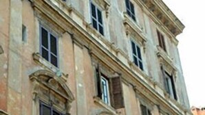 Um edifício de vários andares com arquitetura clássica, com janelas em arco e molduras decorativas.