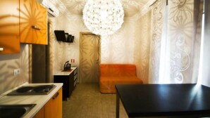 Quarto compacto com cozinha compacta, um lustre redondo, um sofá e uma cama.