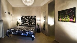 Quarto com cama, lustre, pintura e espelho.