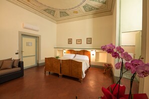 Quarto de hotel com uma cama, um sofá, uma mesa pequena e um espelho.