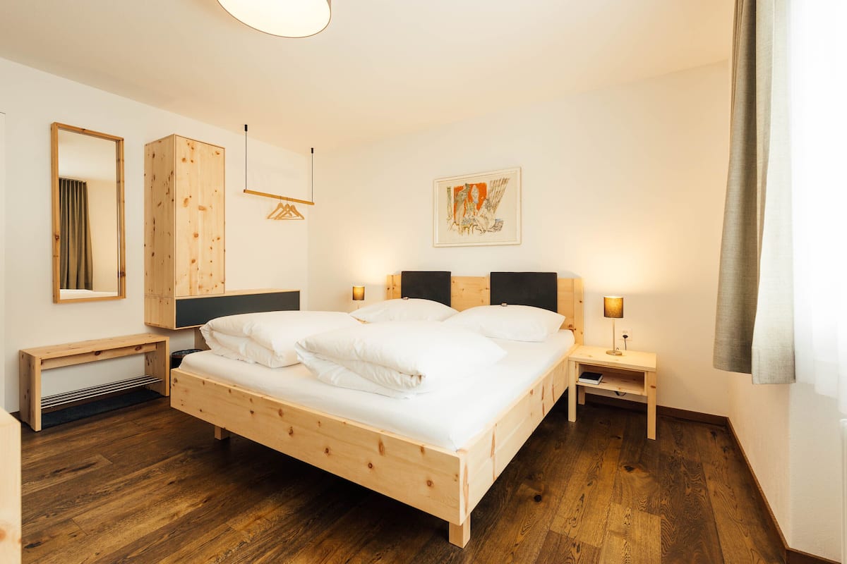 Quarto com cama de madeira, mesas de cabeceira, guarda-roupa e um quadro na parede.