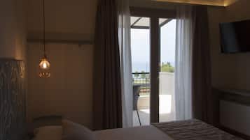 Quarto de hotel com uma cama, uma TV fixada na parede e vista para o exterior por uma porta de correr.