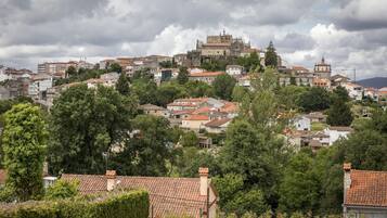 Uma cidade histórica com uma igreja imponente em uma colina, rodeada por edifícios residenciais e vegetação exuberante.