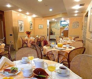 Uma sala de jantar com mesas preparadas para o café da manhã, incluindo pratos de comida, xícaras e copos de suco de laranja.