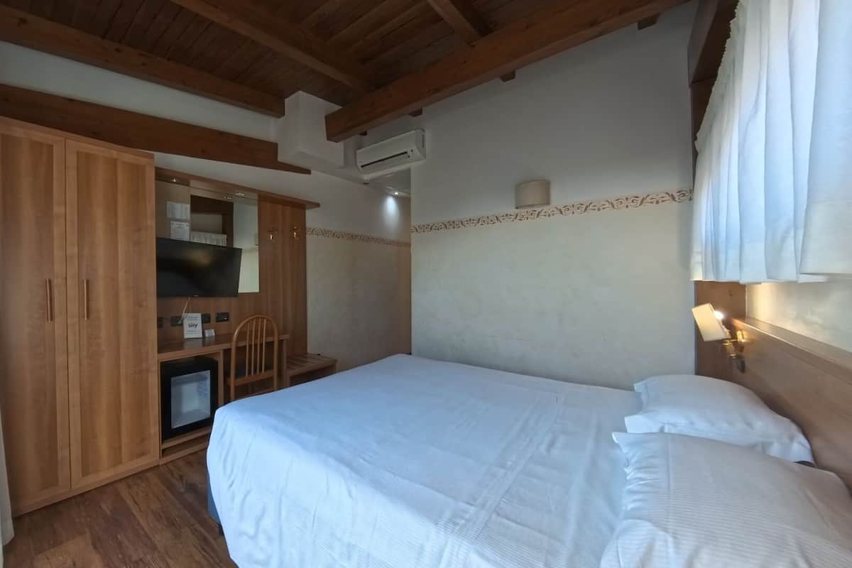 Quarto com cama, guarda-roupa de madeira e televisão.
