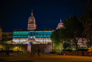 Um edifício histórico com uma torre e uma cúpula imponentes, iluminado durante a noite.