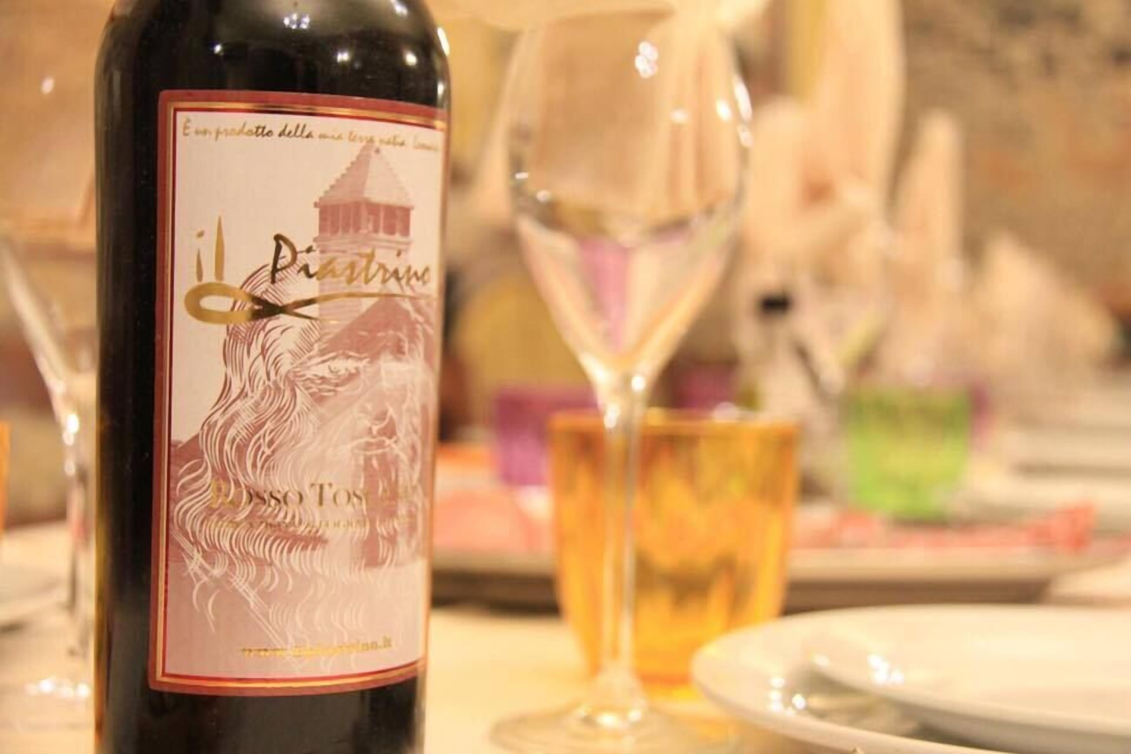 Uma garrafa de vinho com etiqueta detalhada, um copo e um prato sobre uma mesa.