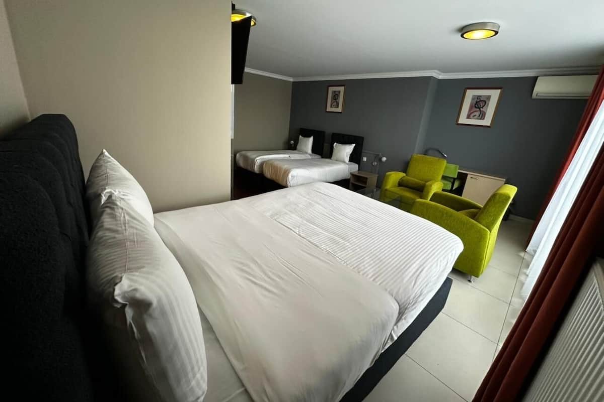 Quarto de hotel com cama, escrivaninha e cadeira.
