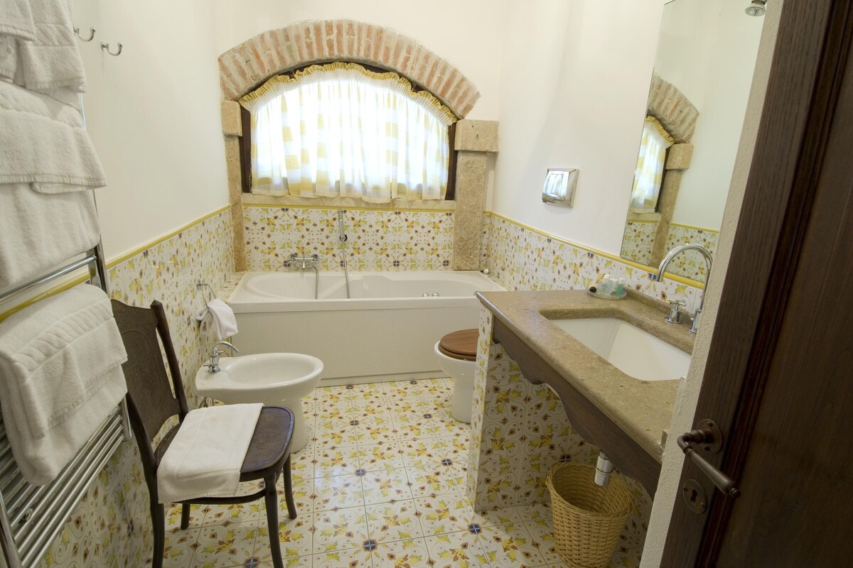 Uma casa de banho com banheira, pia, cadeira e espelho.