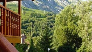 Uma escadaria de madeira leva a uma varanda com vista para uma montanha e uma piscina com espreguiçadeiras.