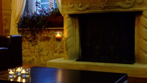 Um quarto com lareira, uma mesa com velas e uma janela com cortinas.