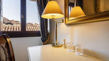 Quarto de hotel com uma mesa, uma lâmpada, uma pequena estatueta e um espelho.