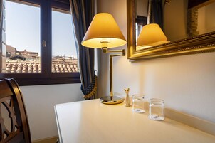 Quarto de hotel com uma mesa, uma lâmpada, uma pequena estatueta e um espelho.