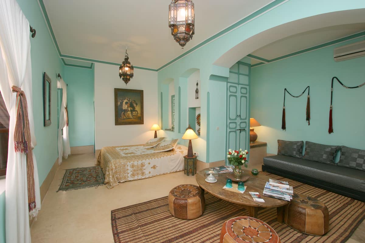 Um quarto com cama, sofá, mesa de centro e abajur.