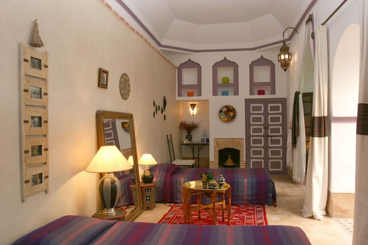 Quarto aconchegante com duas camas, uma lareira e um espelho.