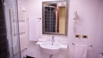 Casa de banho com lavatório branco, espelho com moldura decorativa, porta-toalhas e secador de cabelo.